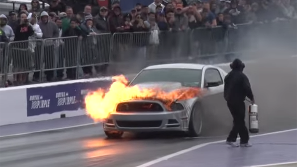 Un Ford Mustang envuelto en llamas en una drag race